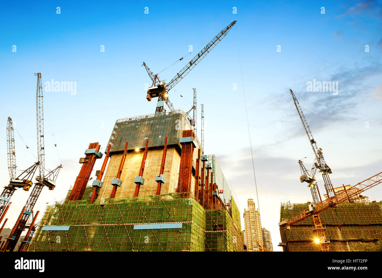 The building is under construction, the dusk site and numerous cranes ...