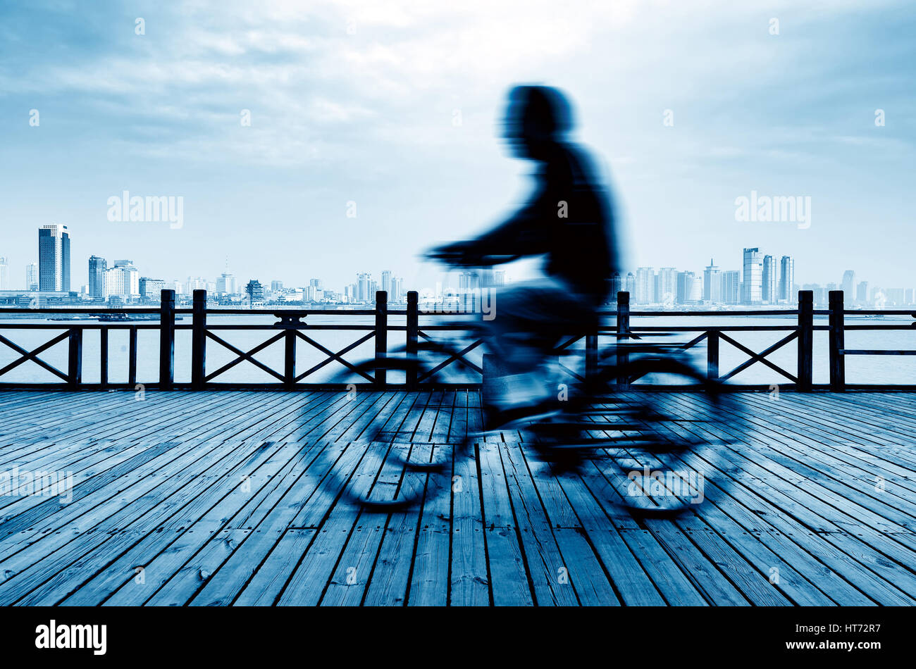 Men ride bicycles through the city's riverside Stock Photo - Alamy