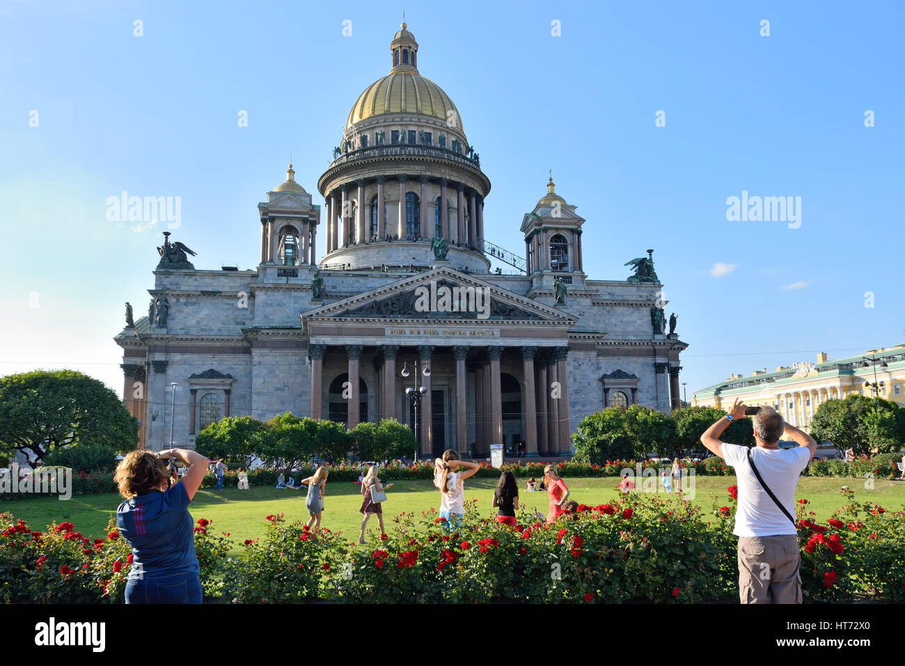 Tourists take pictures of St. Isaac's Cathedral on a background of red ...