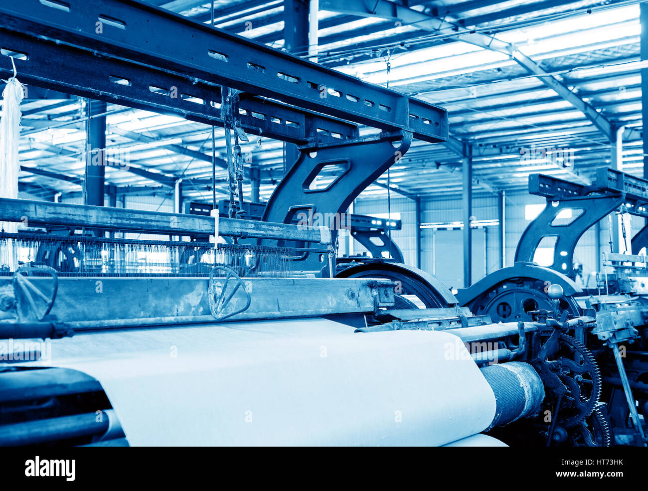 A row of textile looms weaving cotton yarn in a textile mill Stock ...