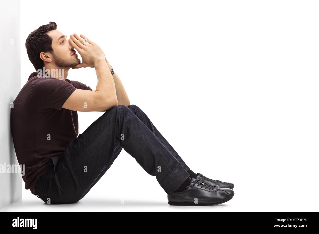 Pensive man leaning against a wall and thinking isolated on white ...