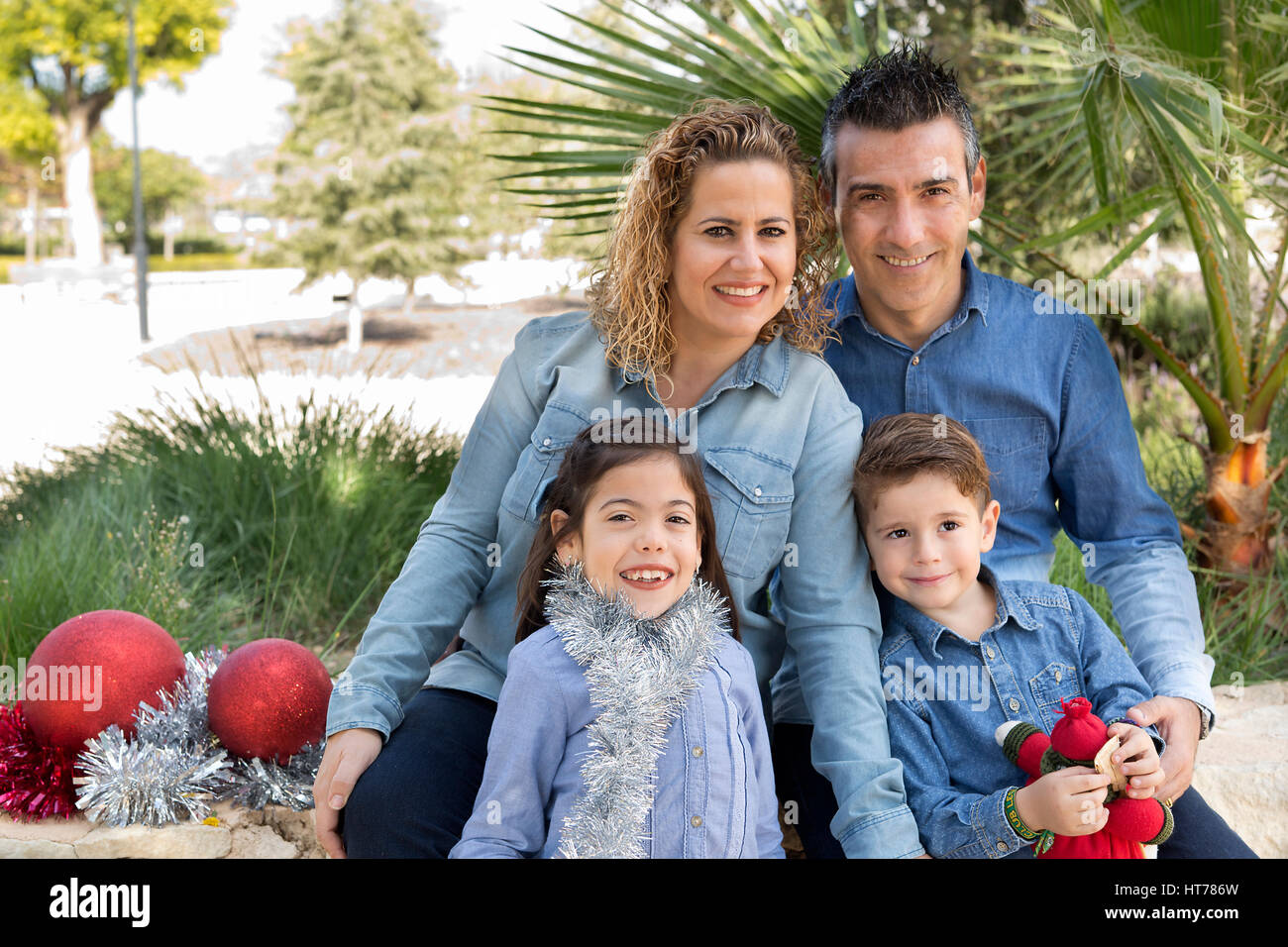 Family of four in a park with Christmas props Stock Photo - Alamy