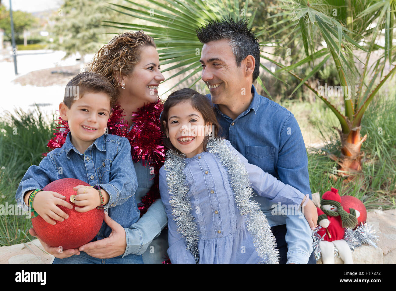 Family of four in a park with Christmas props Stock Photo - Alamy