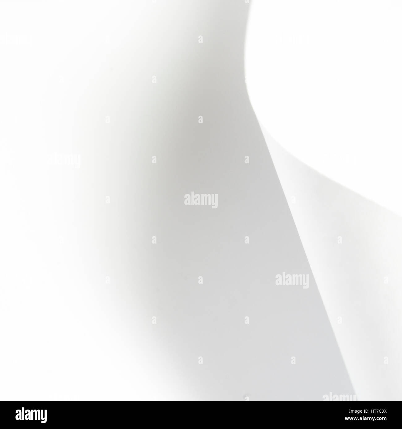 Monochrome photograph of a white piece of paper curled back on itself ...