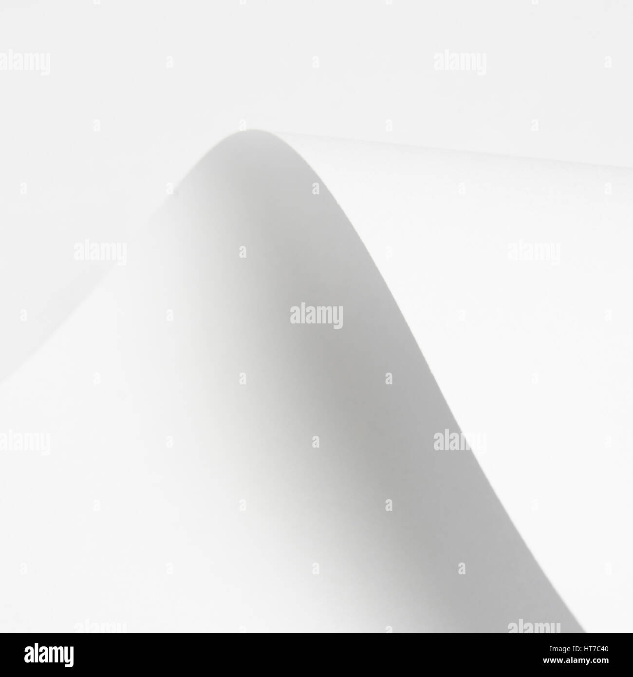 Monochrome photograph of a white piece of paper curled back on itself ...