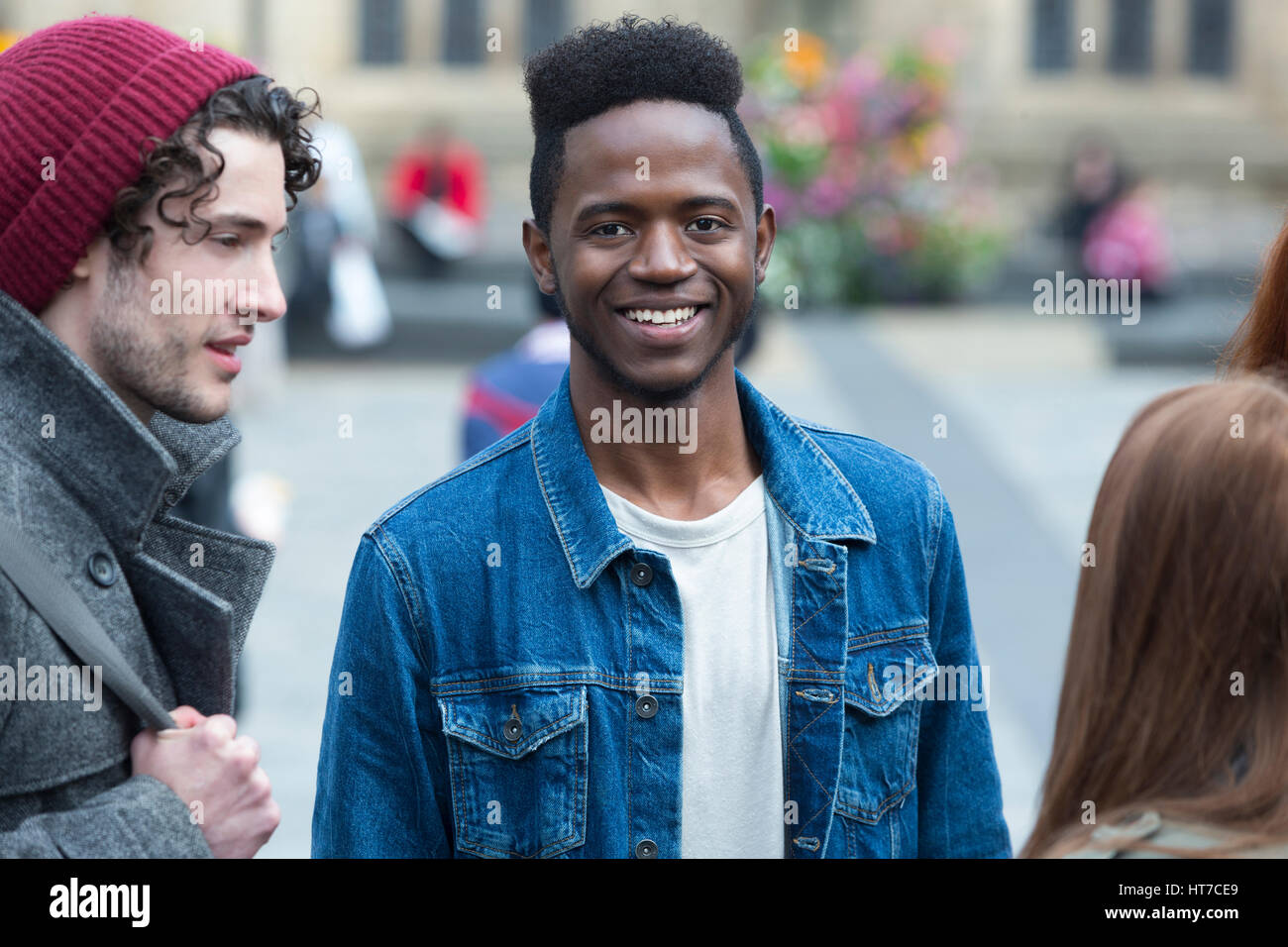 A happy young man smiles at the camera as he stands in his friendship ...