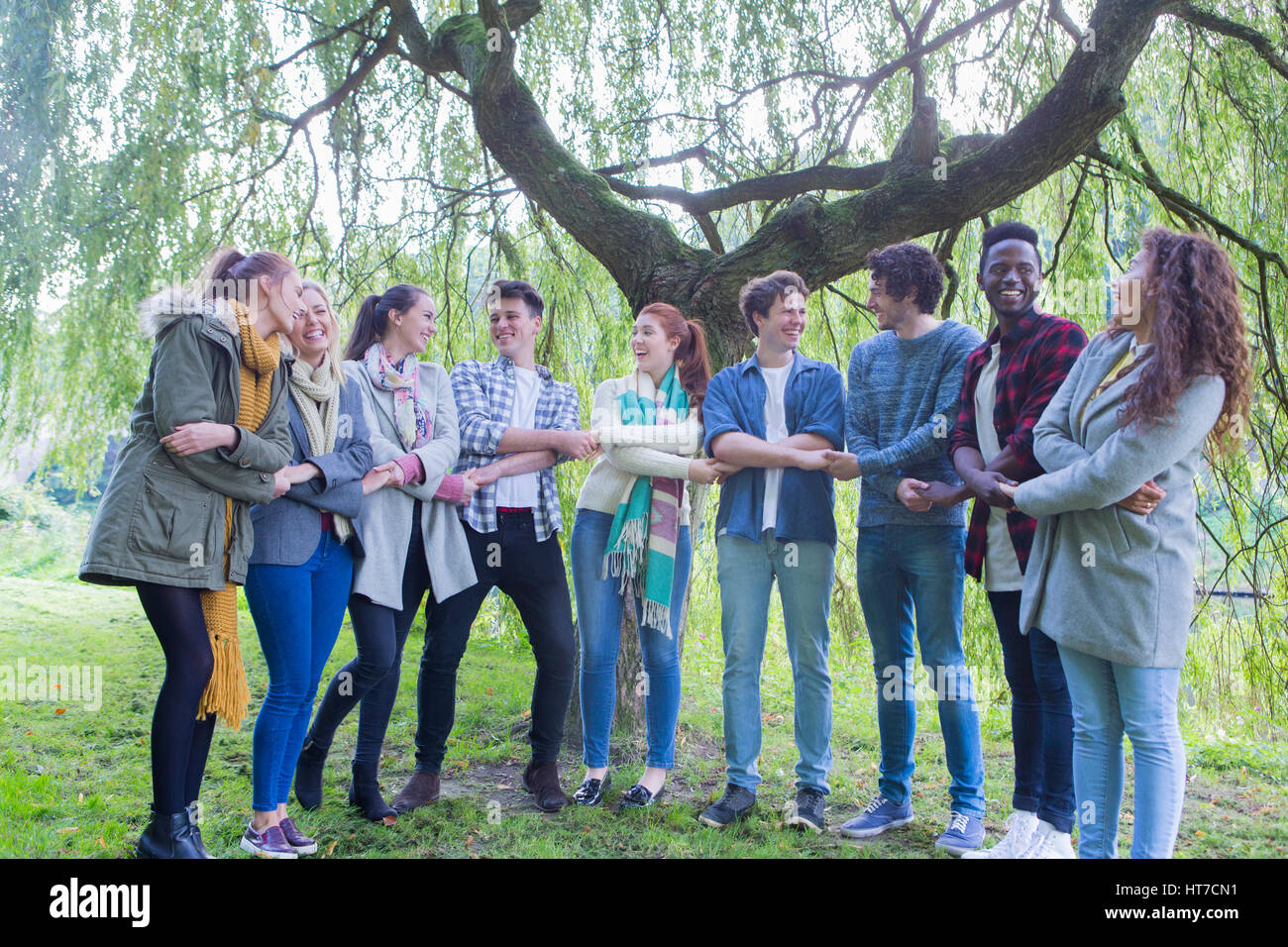 A group of nine students laugh and smile together as they hold hands by ...