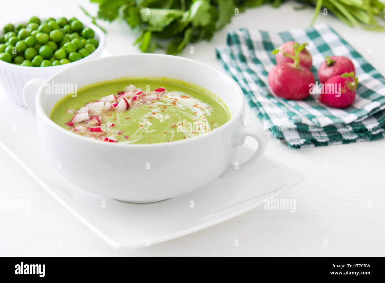 Pea cream with radishes on white wood Stock Photo - Alamy