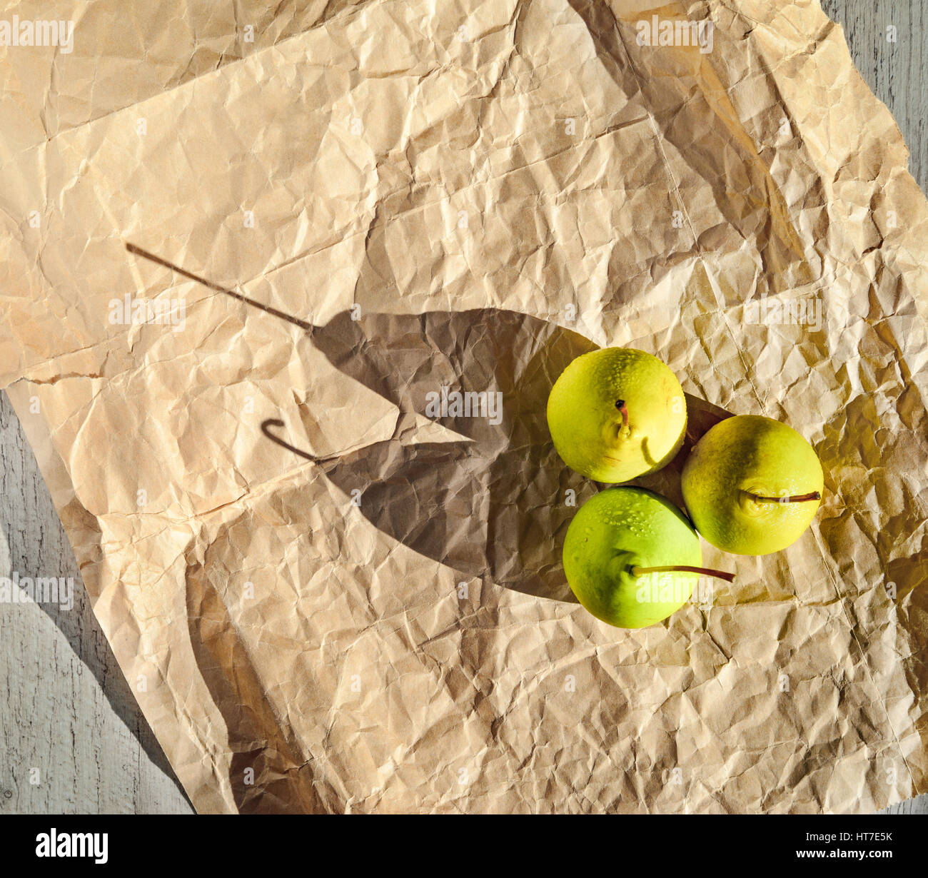 Three ripe pears on crumpled paper cast long shadows Stock Photo - Alamy