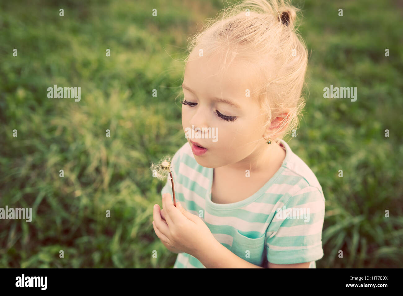 Adorable little blond girl with dandelion flower. Happy kid having fun ...