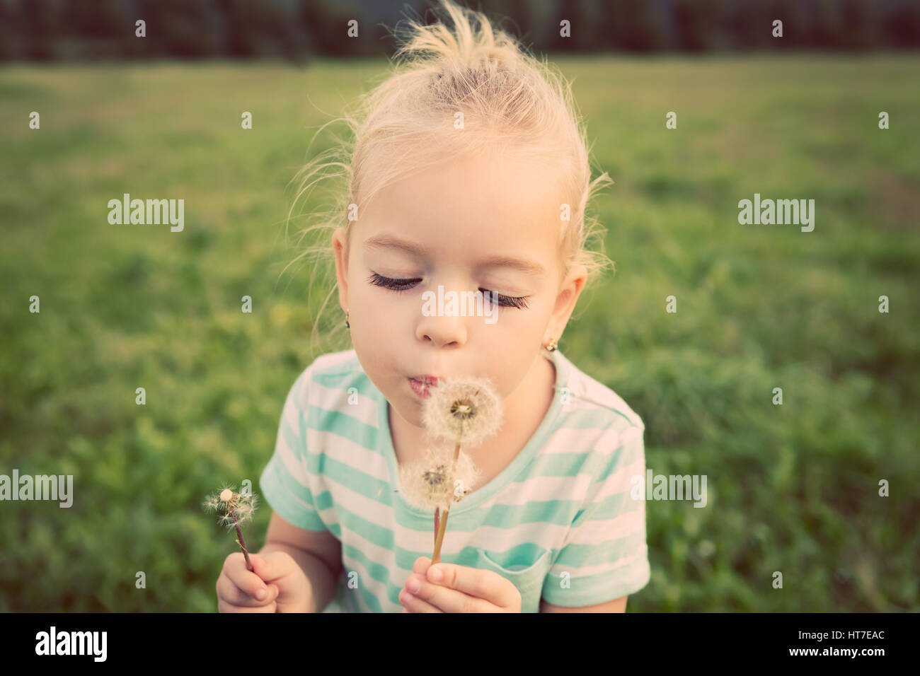 Adorable little blond girl with dandelion flower. Happy kid having fun ...