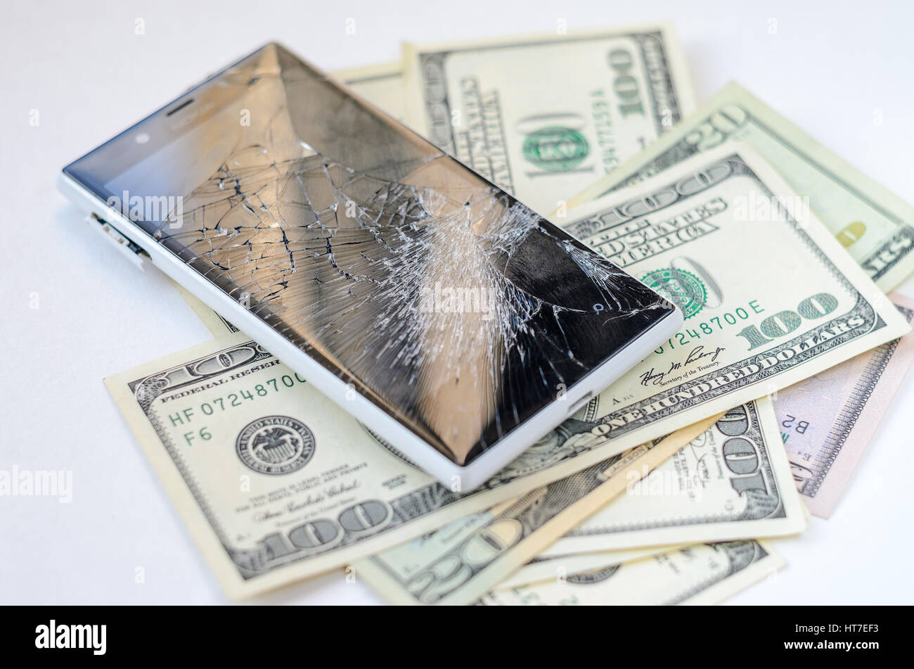 Smartphone with broken display lying on money banknotes on white ...