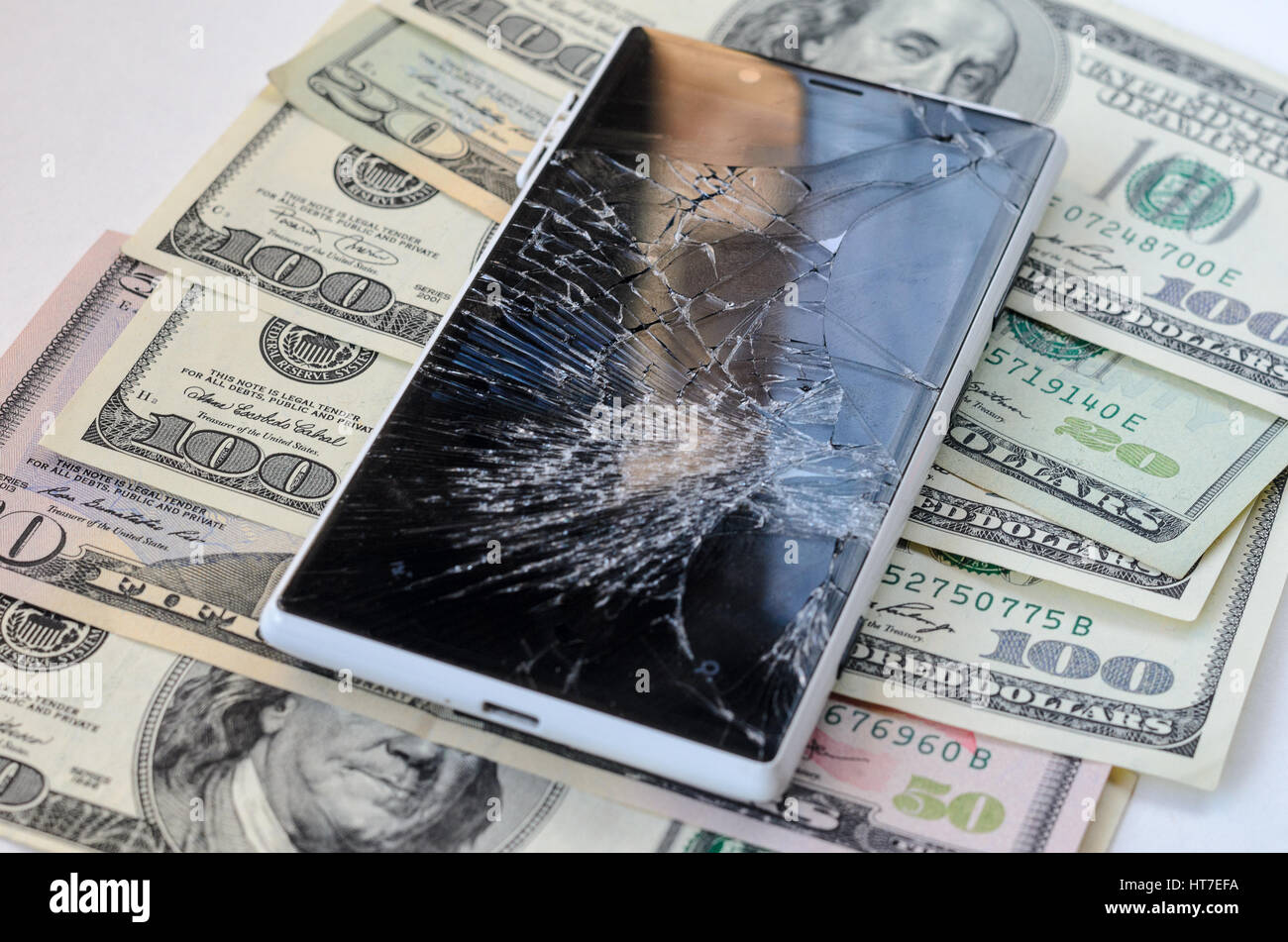 Smartphone with broken displayon money background. Loss of money ...