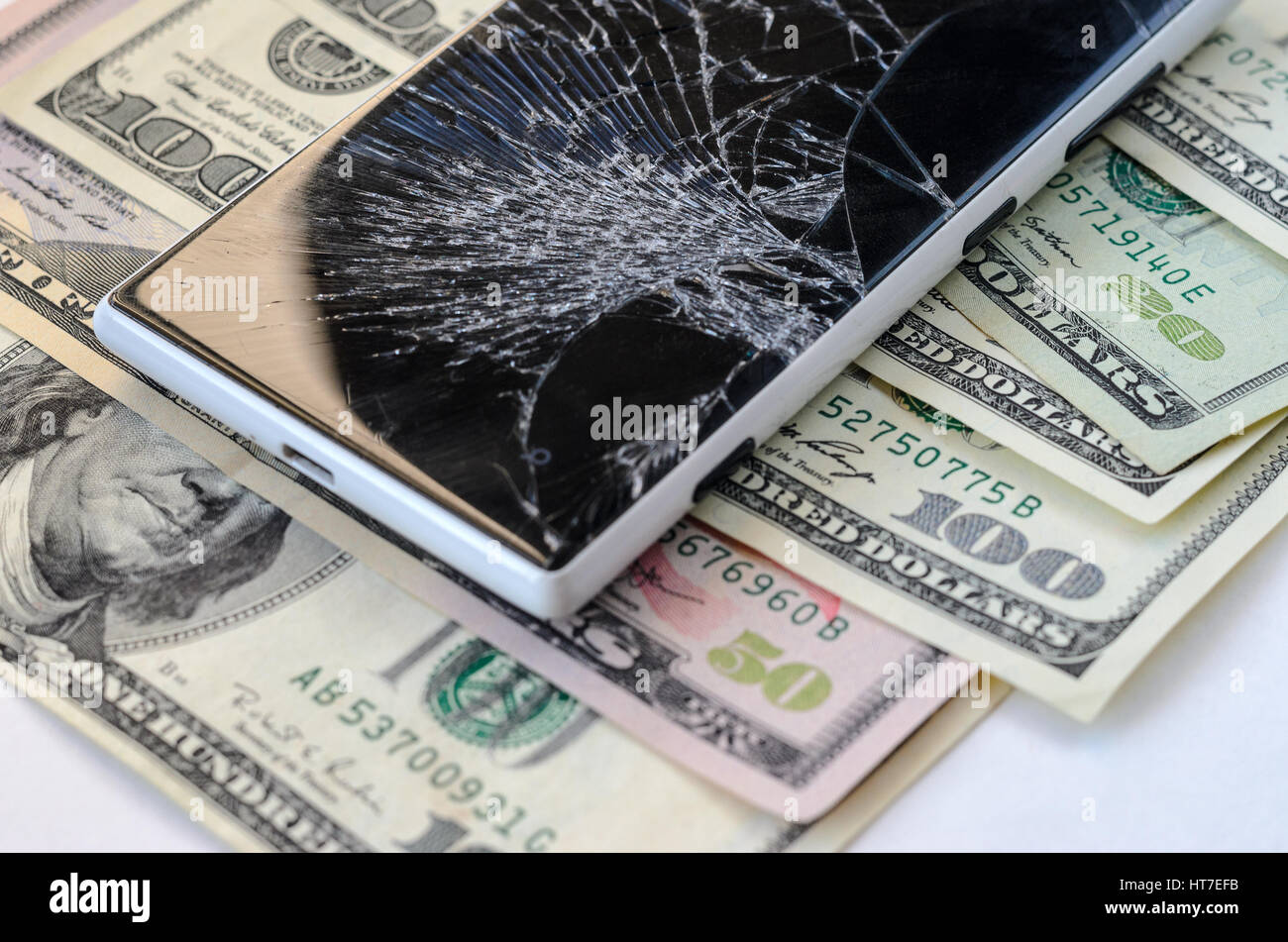 Smartphone with broken displayon money background. Loss of money ...