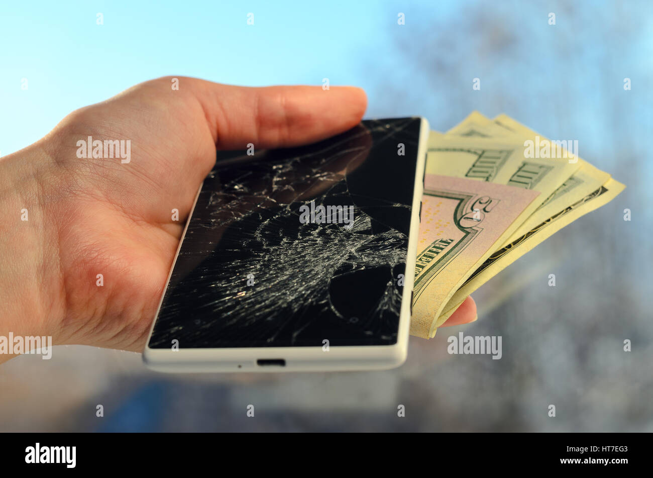 White Smartphone with broken screen in human hands on blured nature ...