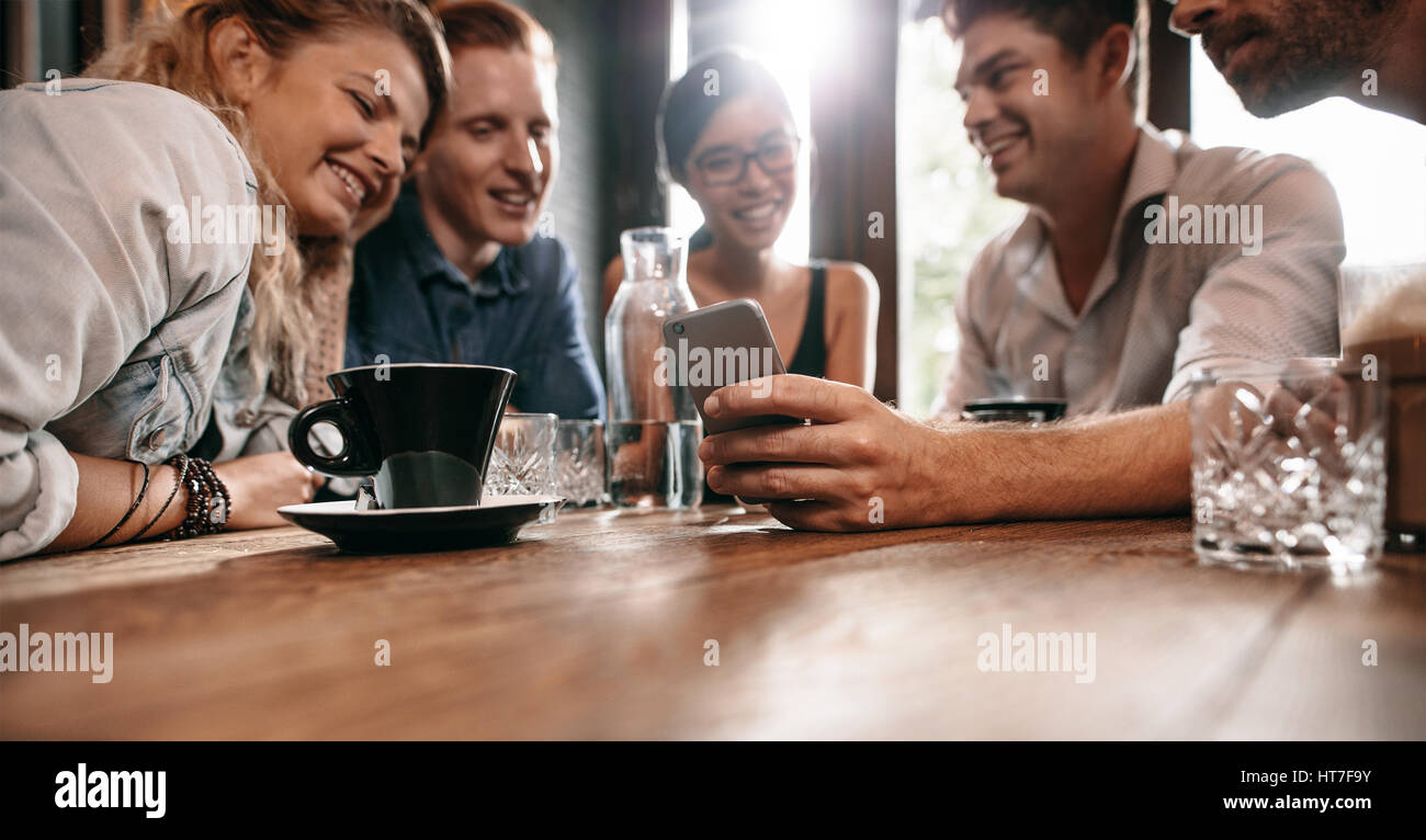 Horizontal shot of young friends watching photos on mobile phone. Group ...