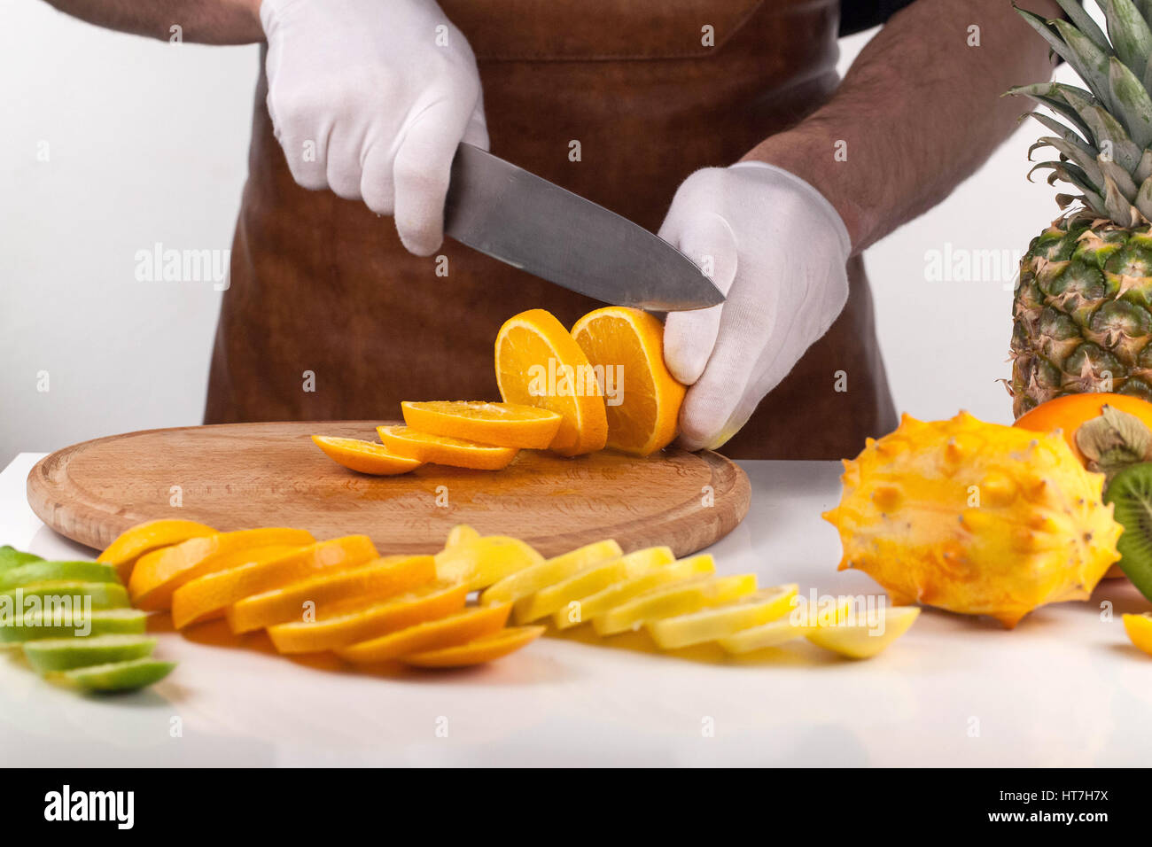 Chef cutting a fruit on a wooden cutting board. Composition of fruits ...