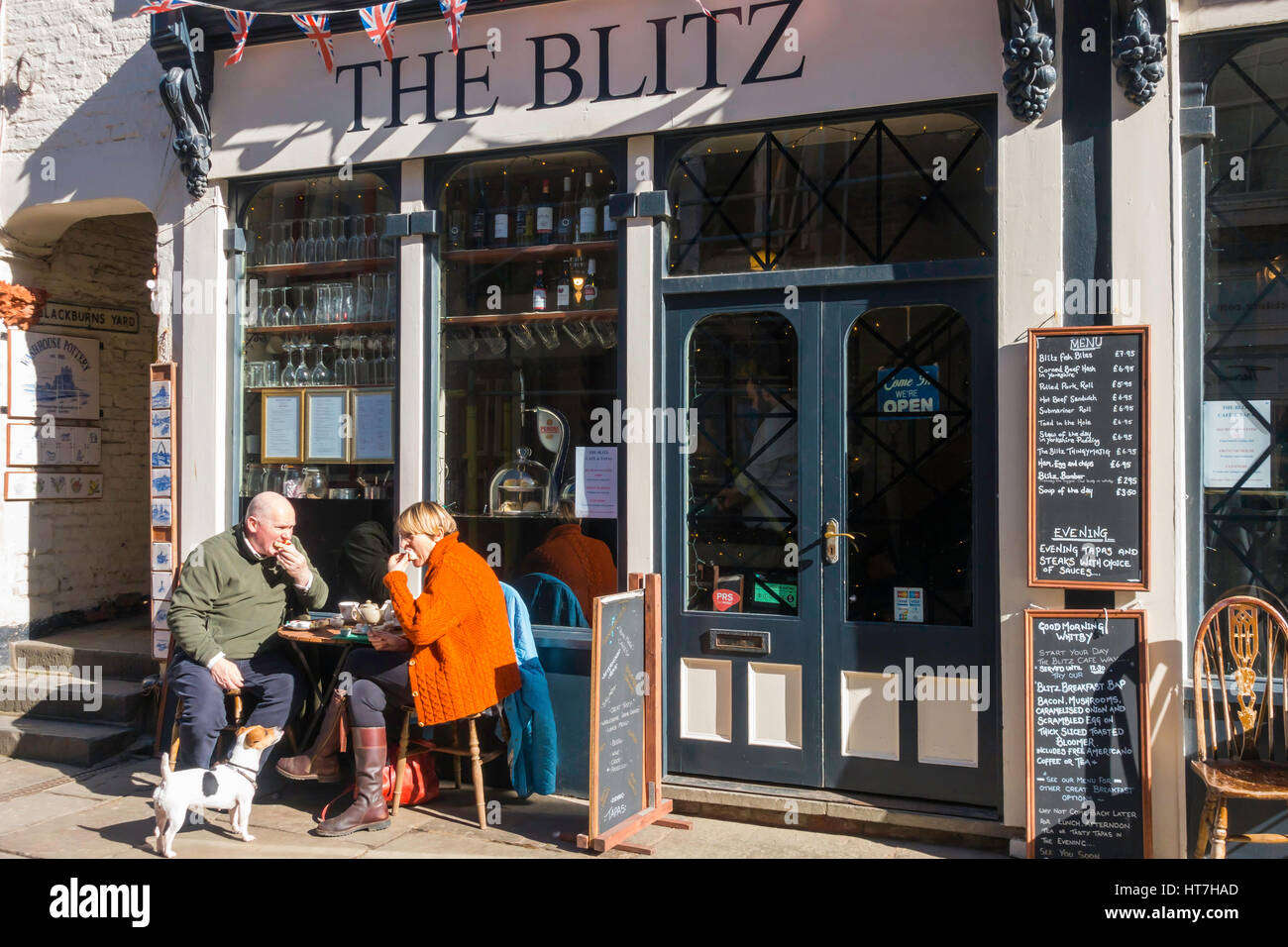 A couple with a Jack Russell dog enjoying lunch in spring sunshine at ...