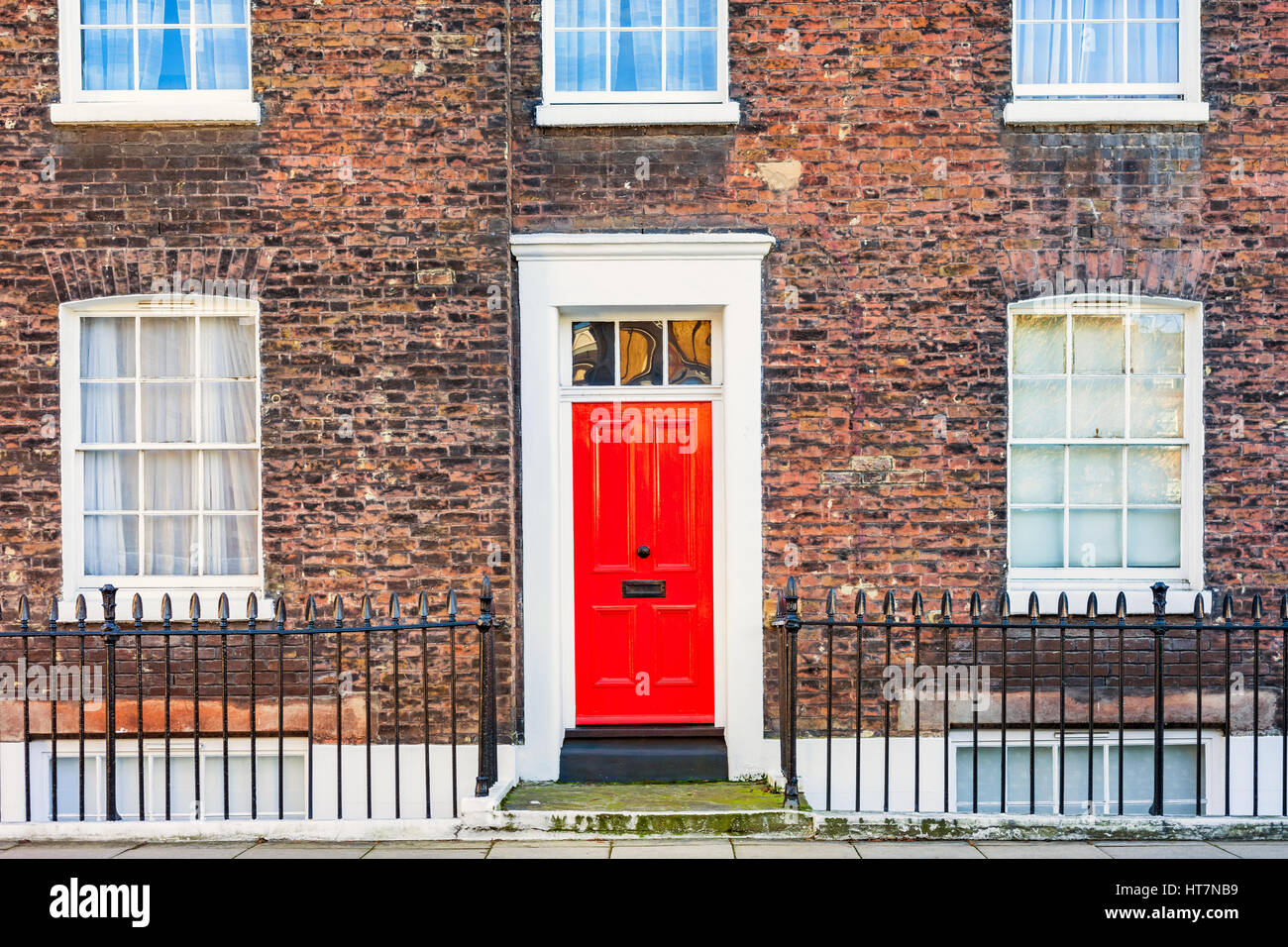 Brick facade apartment house with red front door in London, England, UK ...
