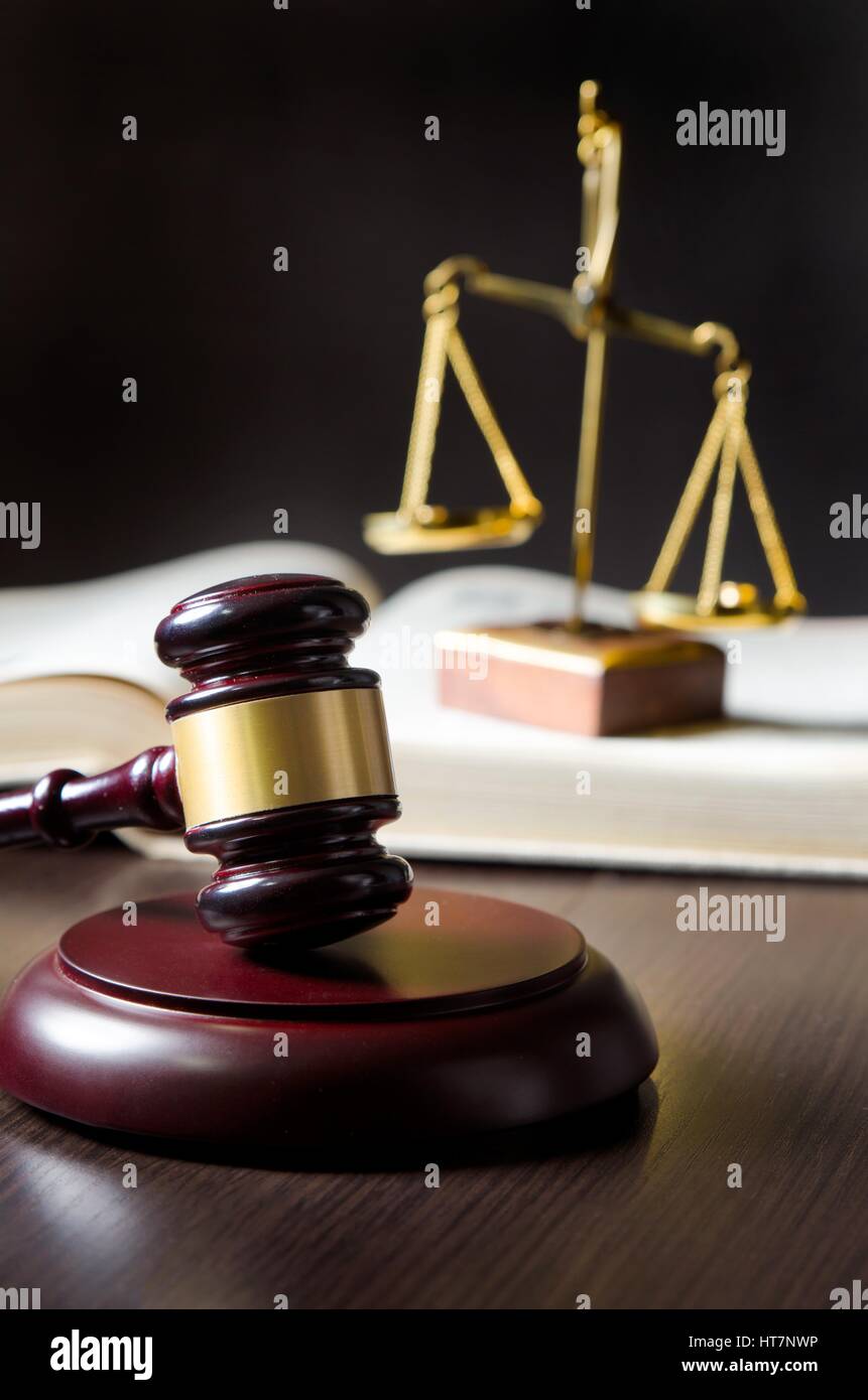 Wooden gavel and books on wooden table. Scale on books in background ...