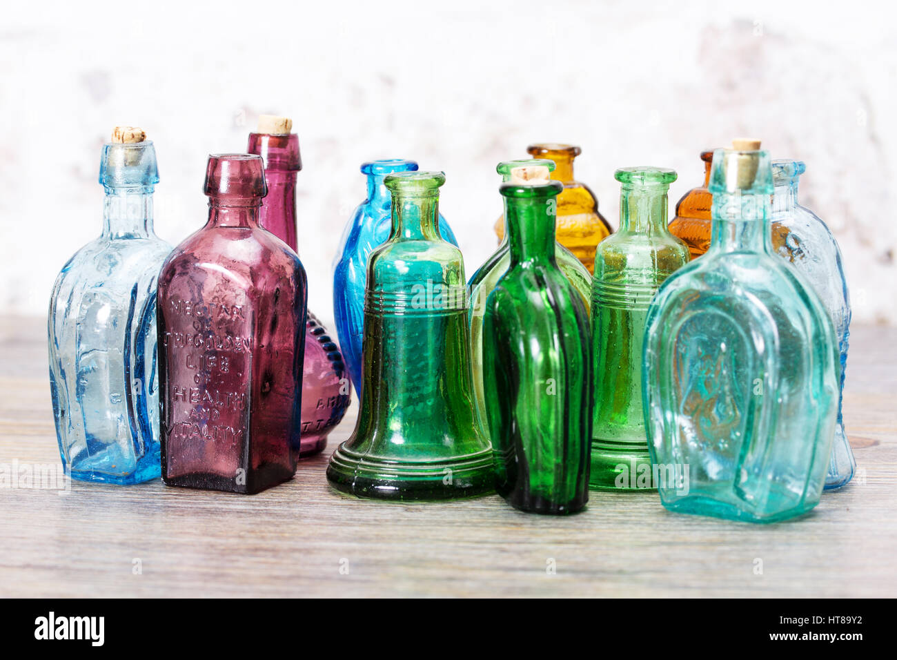 Selection of coloured glass bottles on a rustic background Stock Photo ...