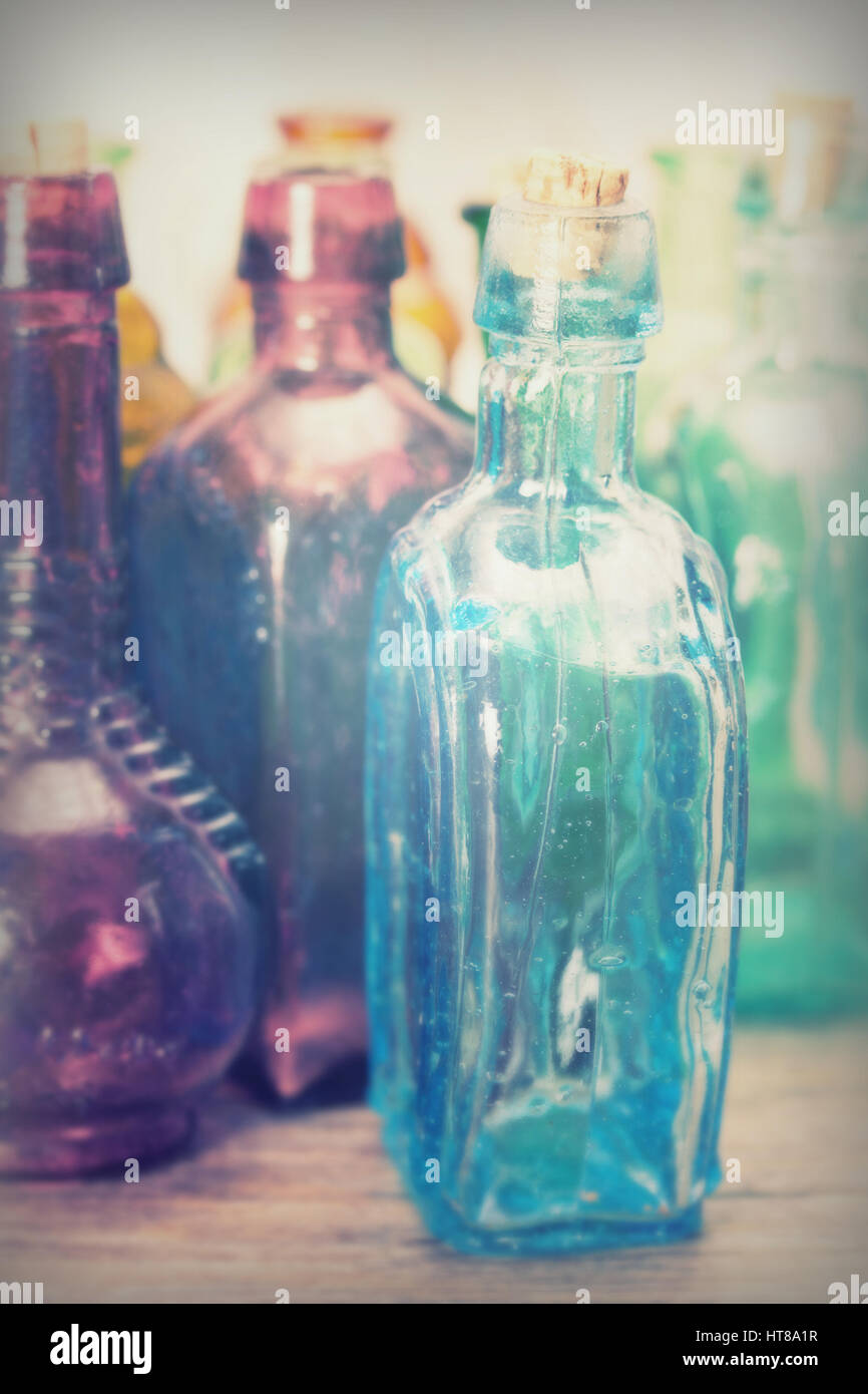 Selection of coloured glass bottles on a rustic background Stock Photo ...