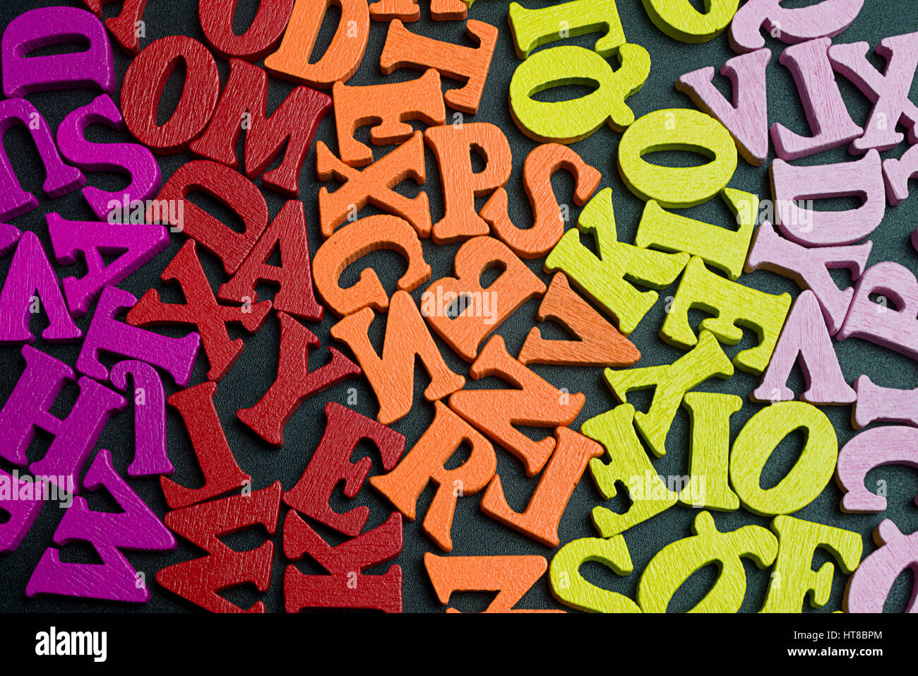 Letters of different colors lie on a black floor Stock Photo - Alamy