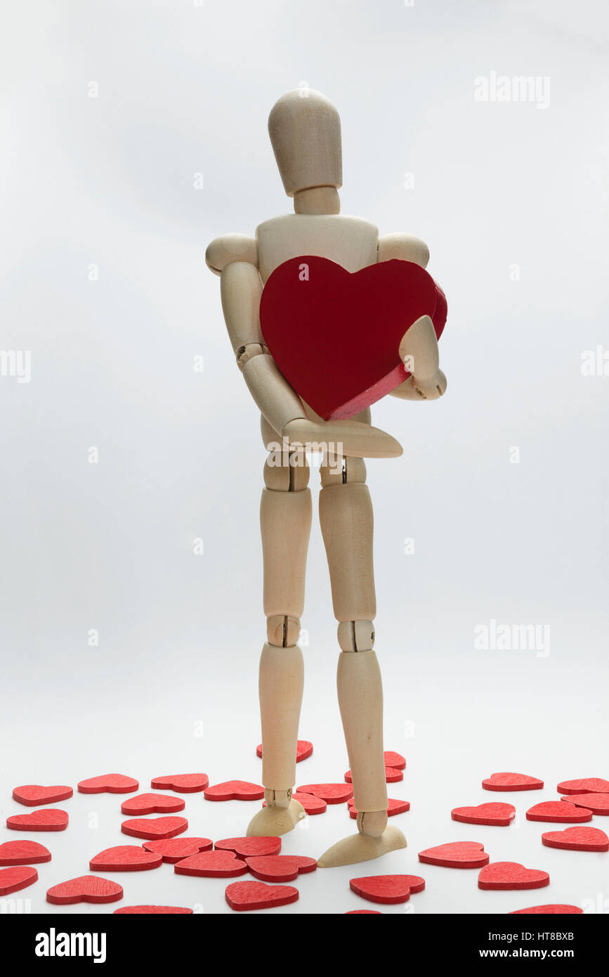 Little wooden man holding a heart on a white background Stock Photo - Alamy