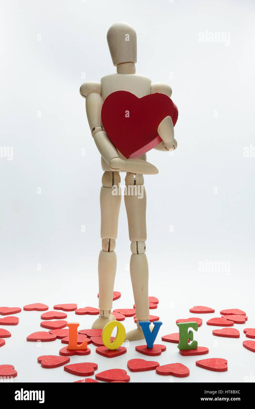 Little wooden man holding a heart on a white background Stock Photo - Alamy