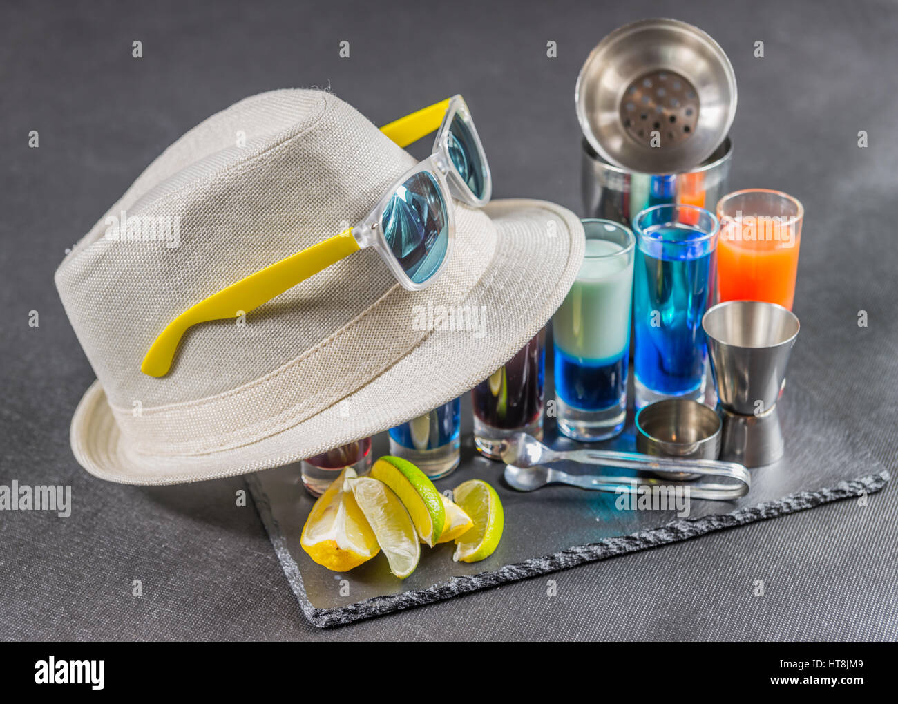six different colored shot drinks, lined up on a black stone plate, ice ...