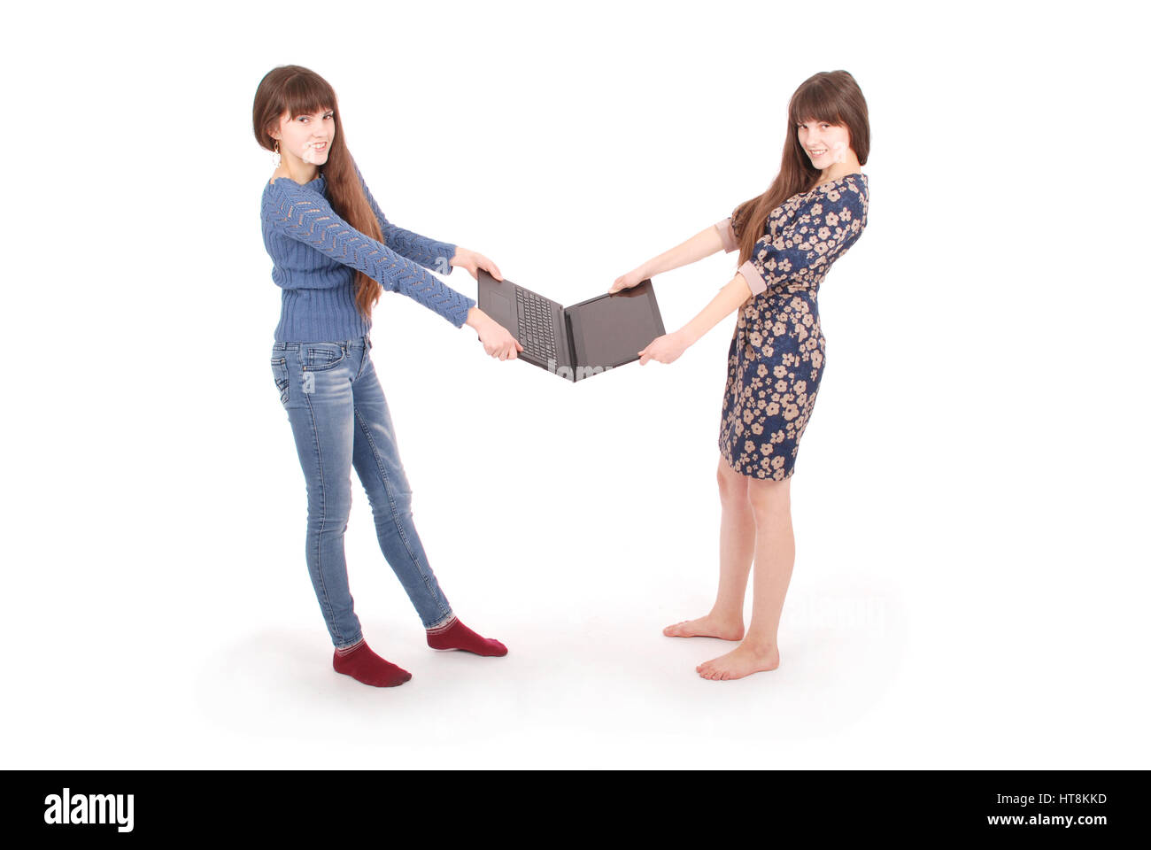 Portrait of two twins sisters with laptop on white background Stock ...