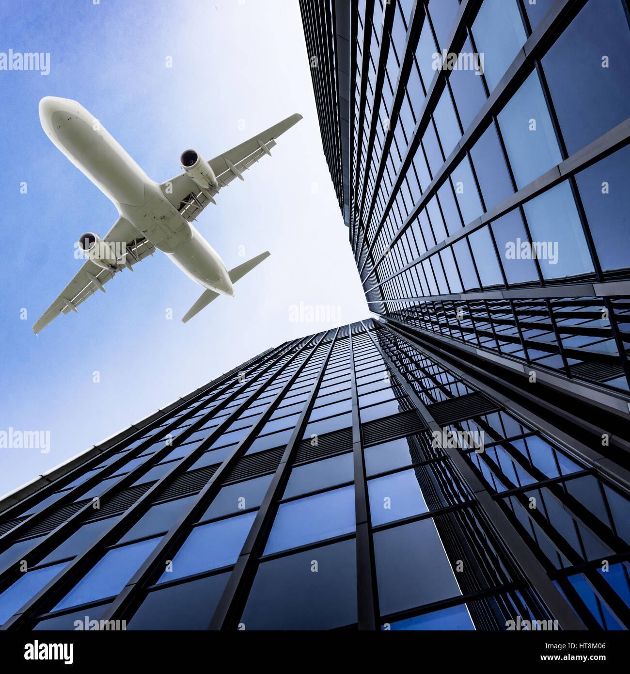 Skyscrapers with a flying airplane against blue sky Stock Photo - Alamy