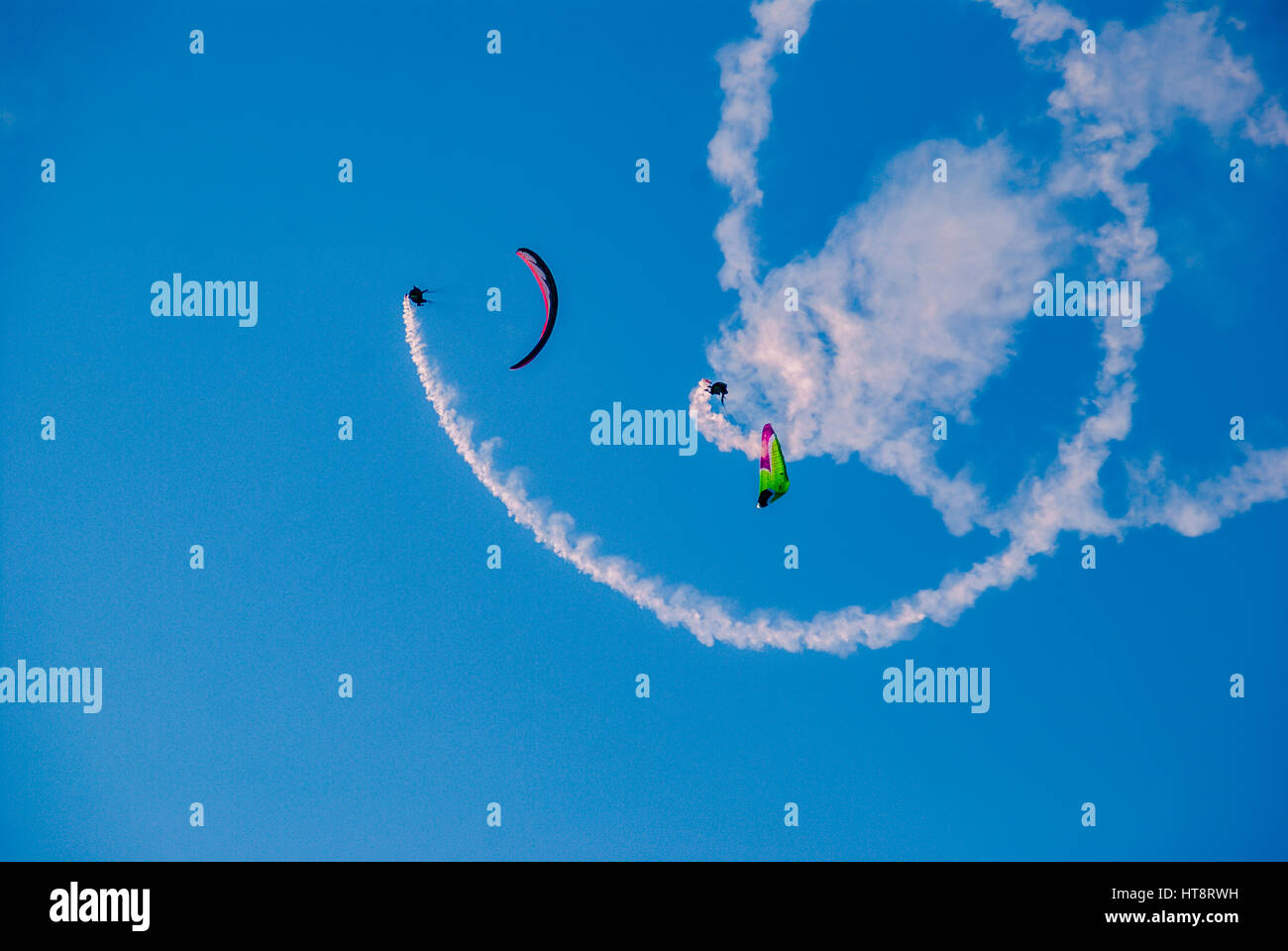 Professional acro pilot performing Paragliding acro show in blue skies ...