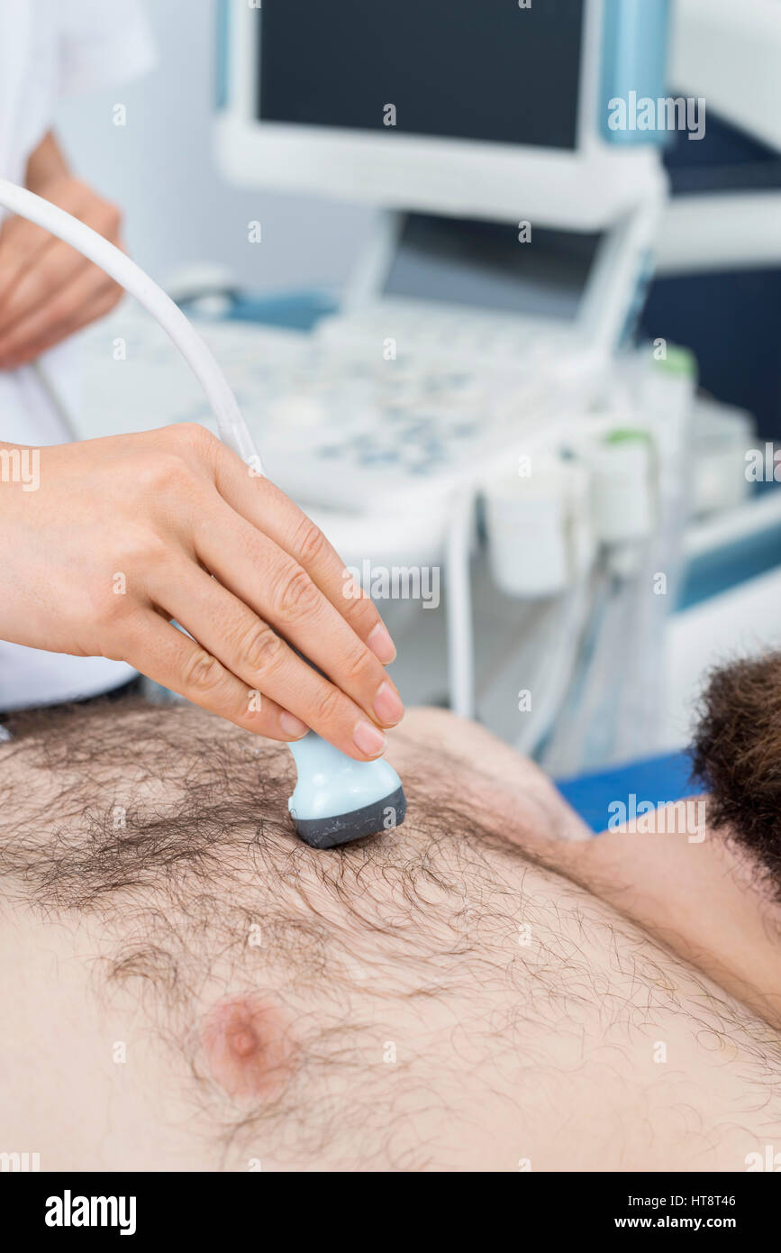 Cropped image of female doctor placing ultrasound probe on male patient ...