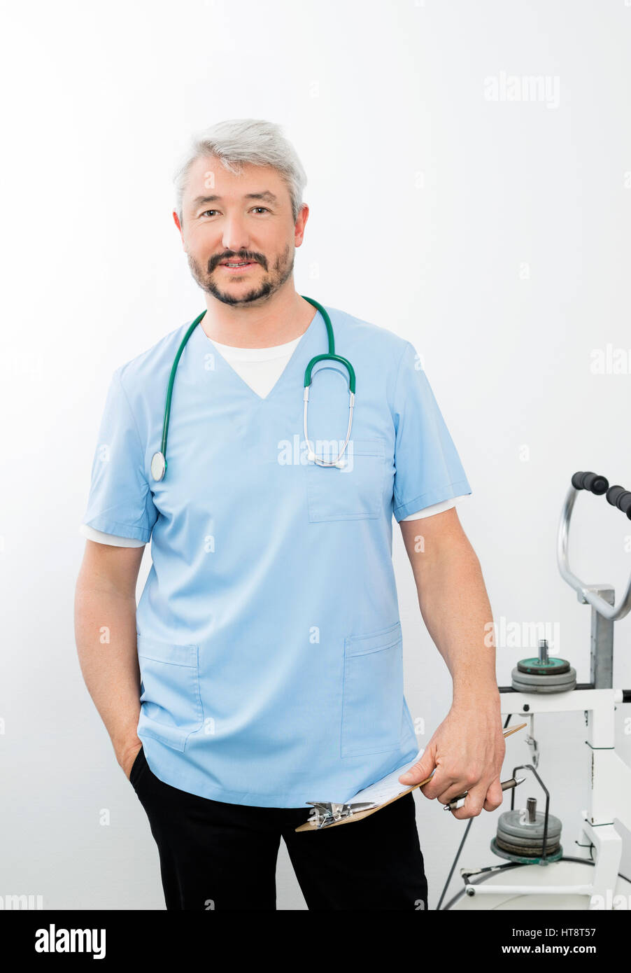 Portrait of confident doctor holding clipboard while standing in ...