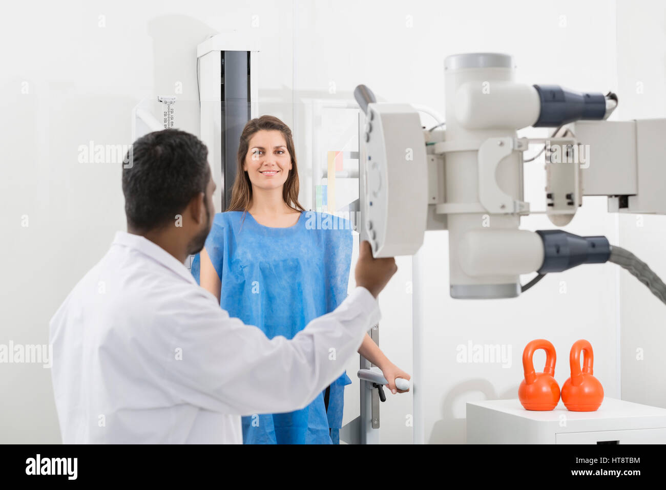 Male radiologist adjusting X-ray machine over female patient in ...