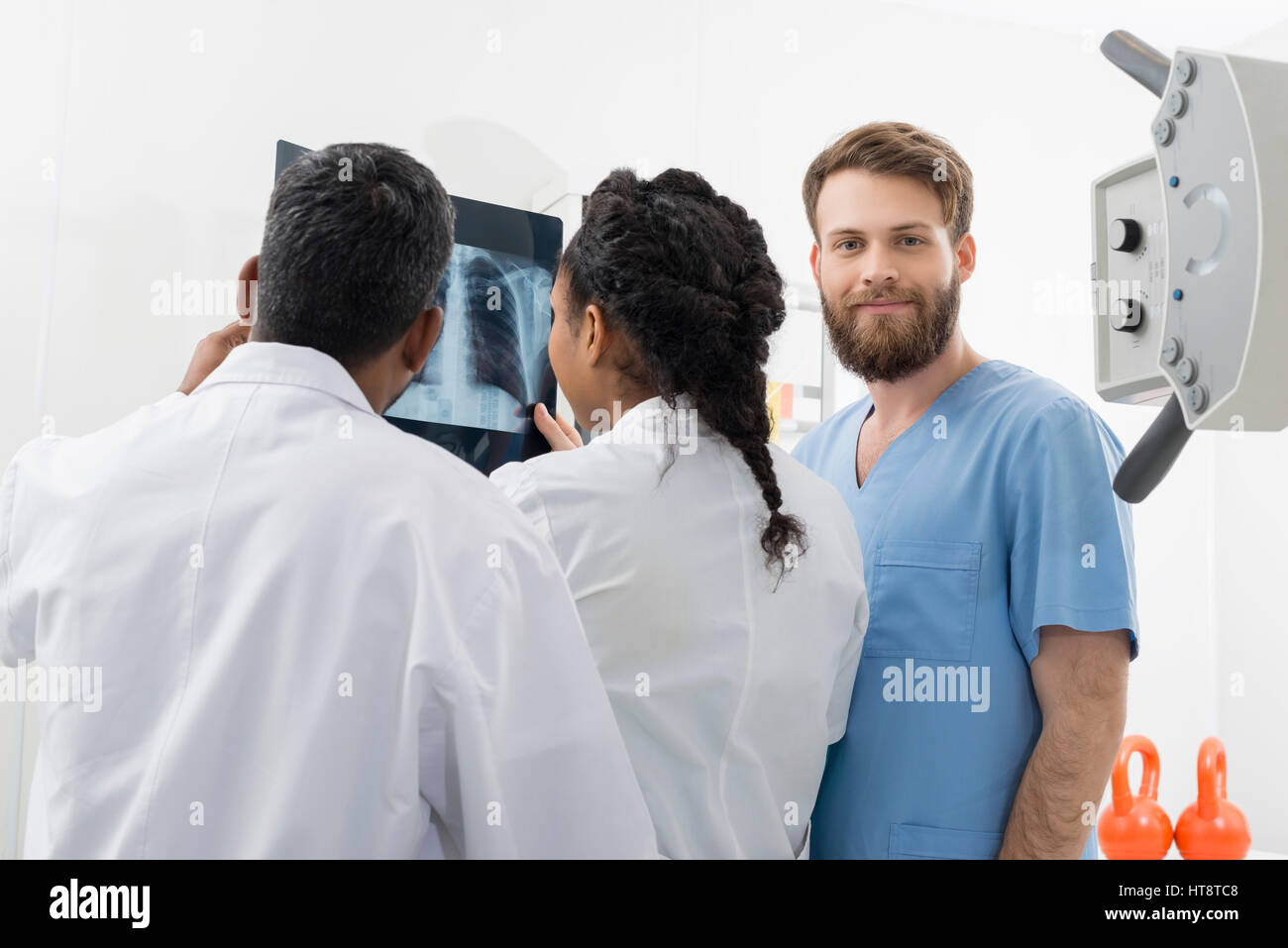 Portrait of male radiologist with colleagues examining X-ray in ...