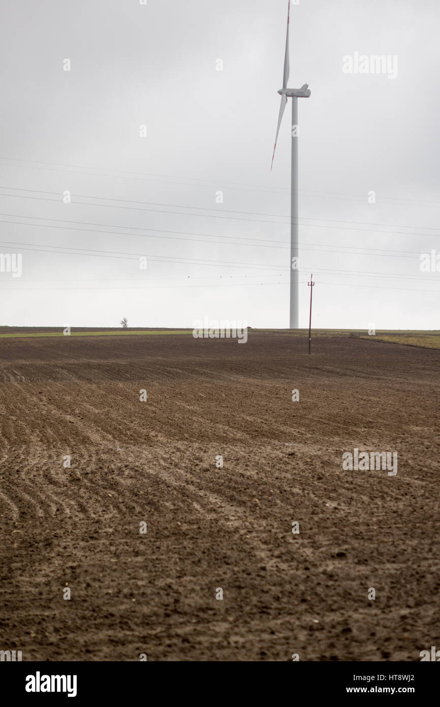 landscape with wind turbines and plowed soil on the empty field at the ...