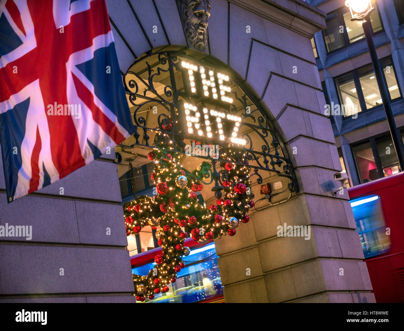 The Ritz Hotel exterior with lit sign at dusk and Union Jack British ...