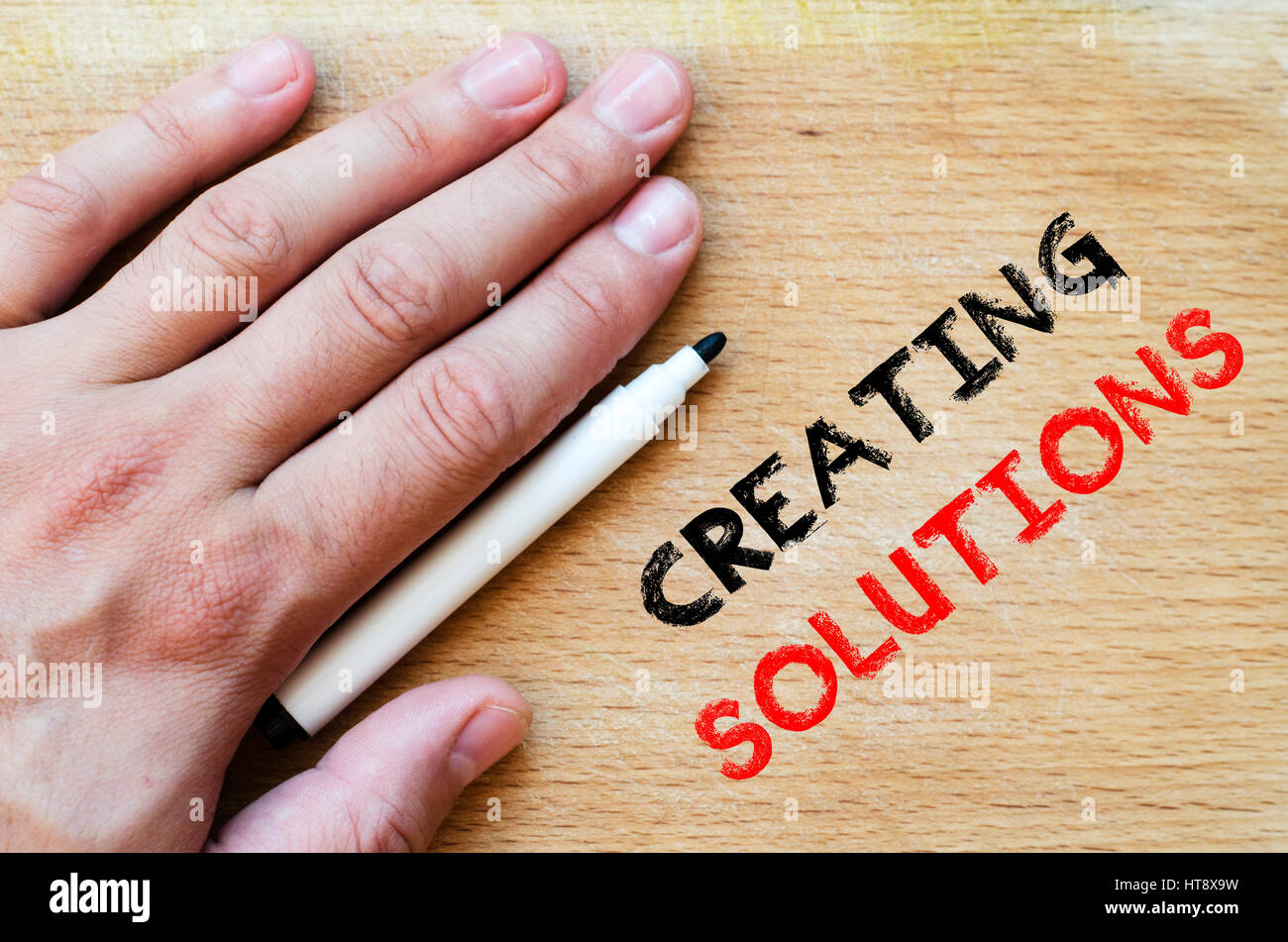 Human hand over wooden background and creating solutions text concept ...