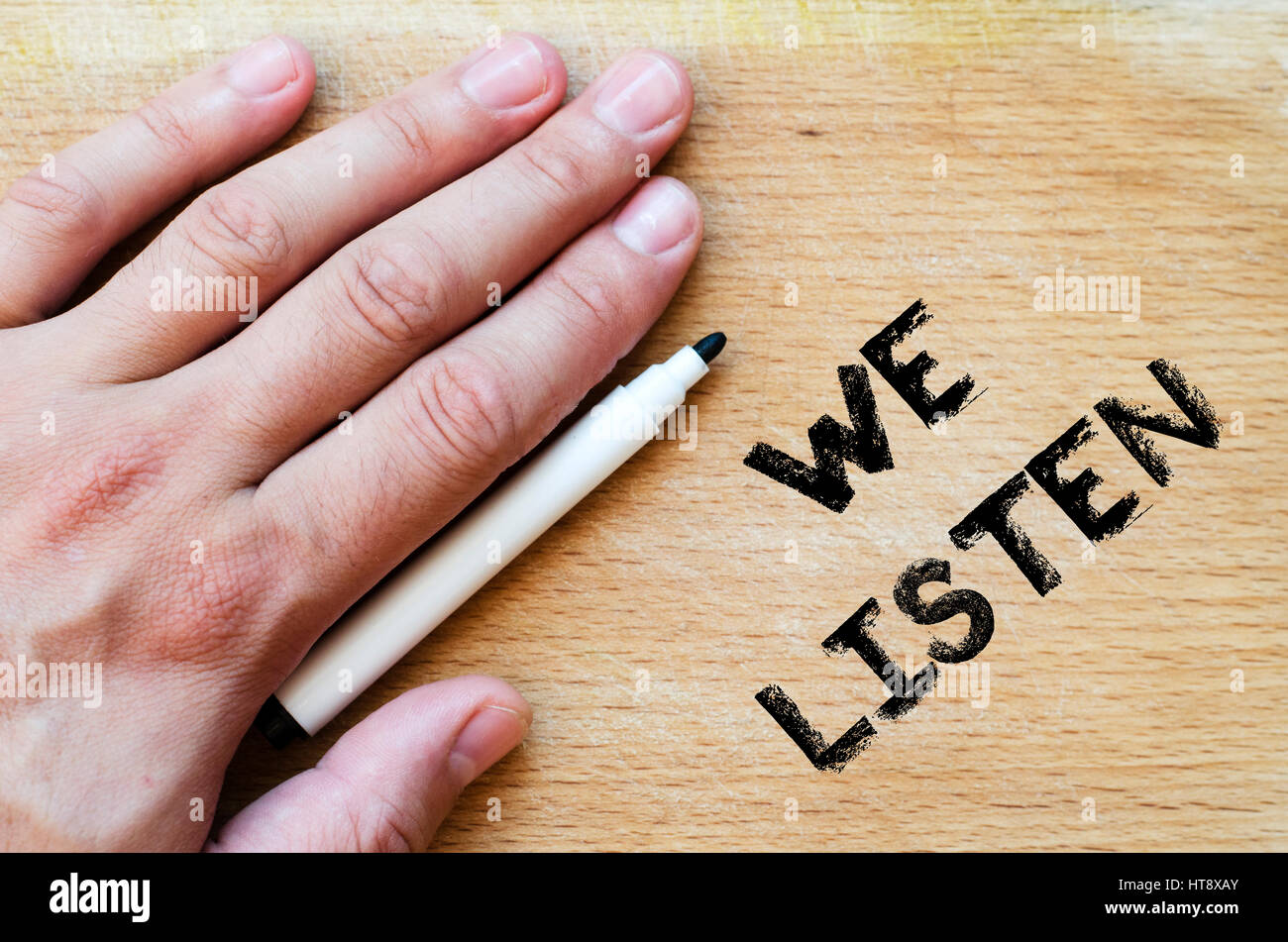 Human hand over wooden background and we listen text concept Stock ...