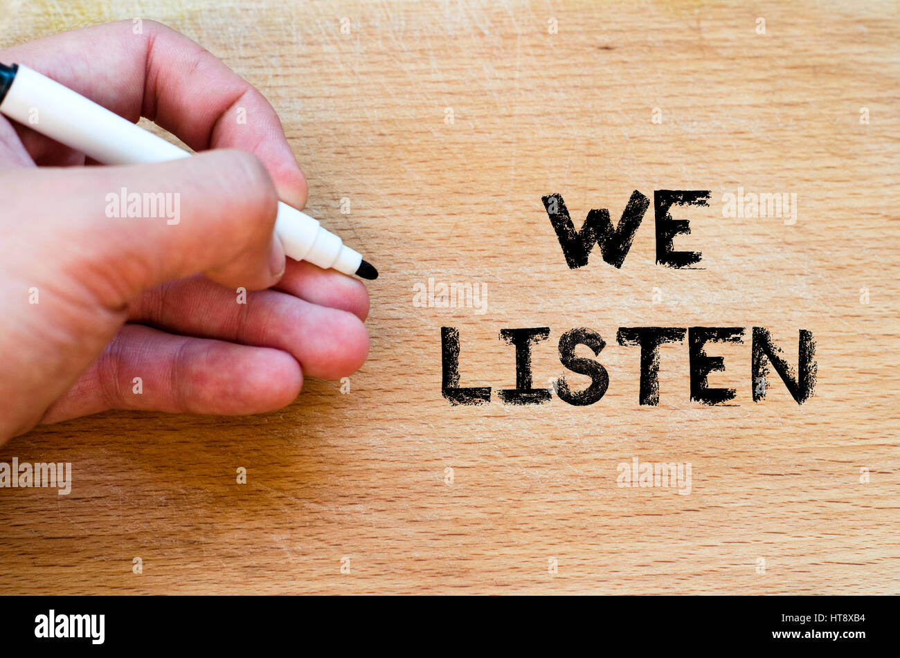 Human hand over wooden background and we listen text concept Stock ...