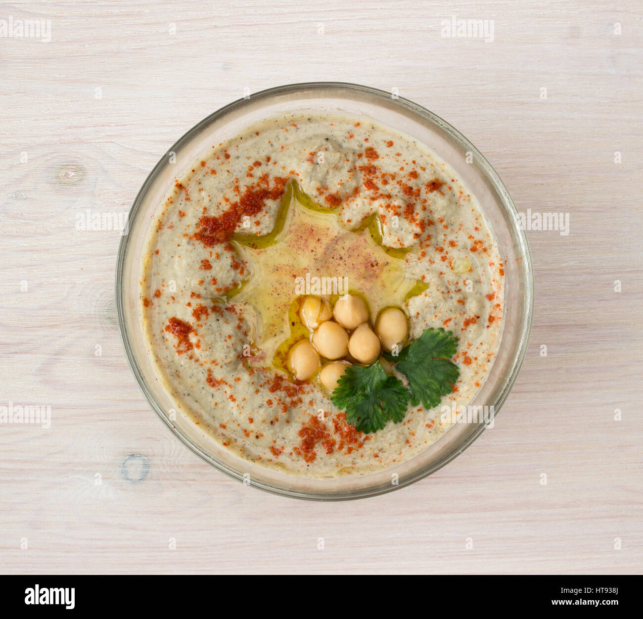 A bowl of creamy hummus with olive oil on light background. horizontal ...