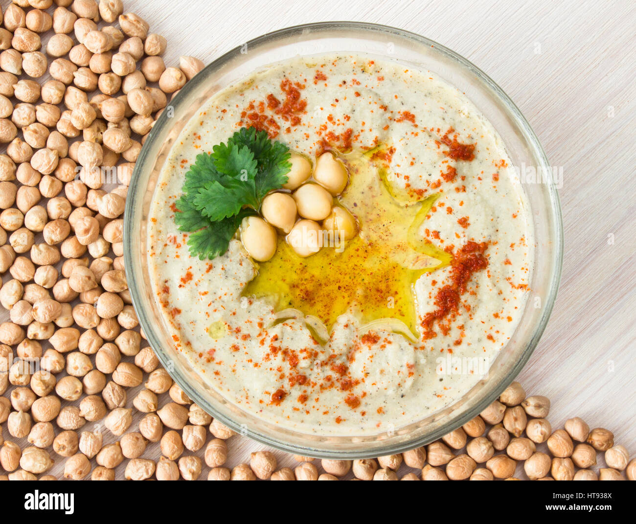 A bowl of creamy hummus with olive oil on light background. horizontal ...