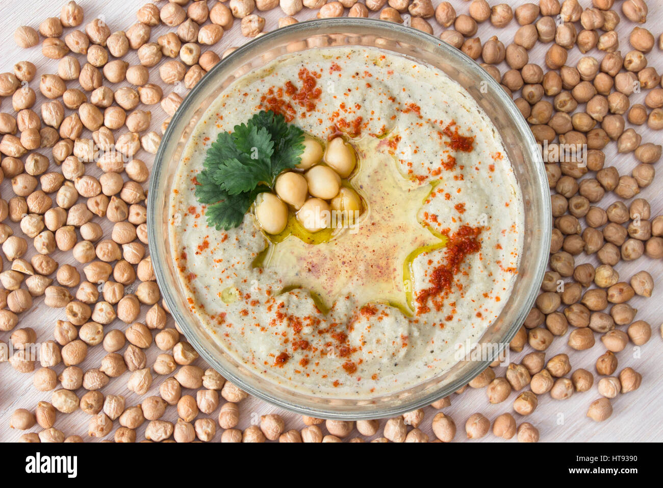 A bowl of creamy hummus with olive oil on light background. horizontal ...