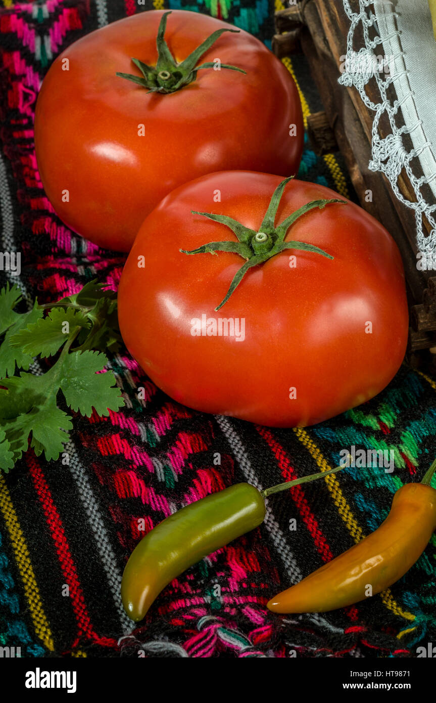 Red tomatoes and chilies over Mexican colorful textile Stock Photo - Alamy