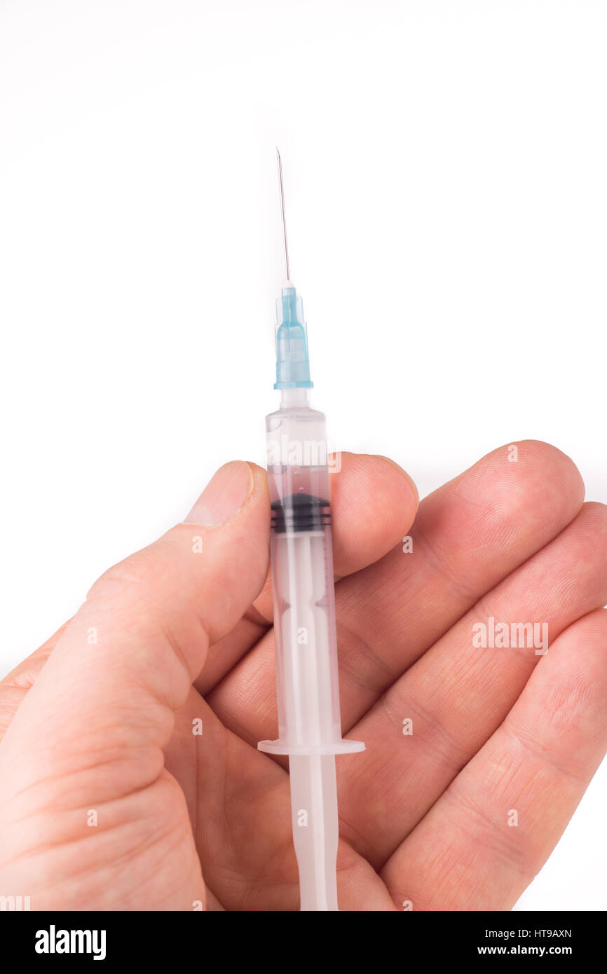 Hand holding a syringe, the syringe is filled with clear liquid and the ...