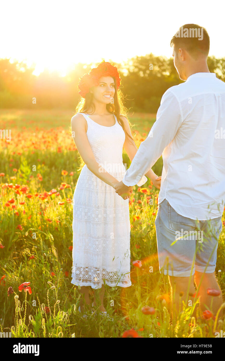 Young couple in love taking hands together at poppy field Stock Photo ...