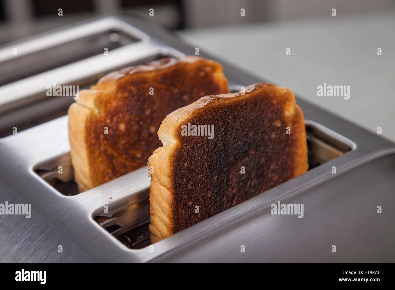 Two slices of burnt toast in a metal toaster Stock Photo - Alamy