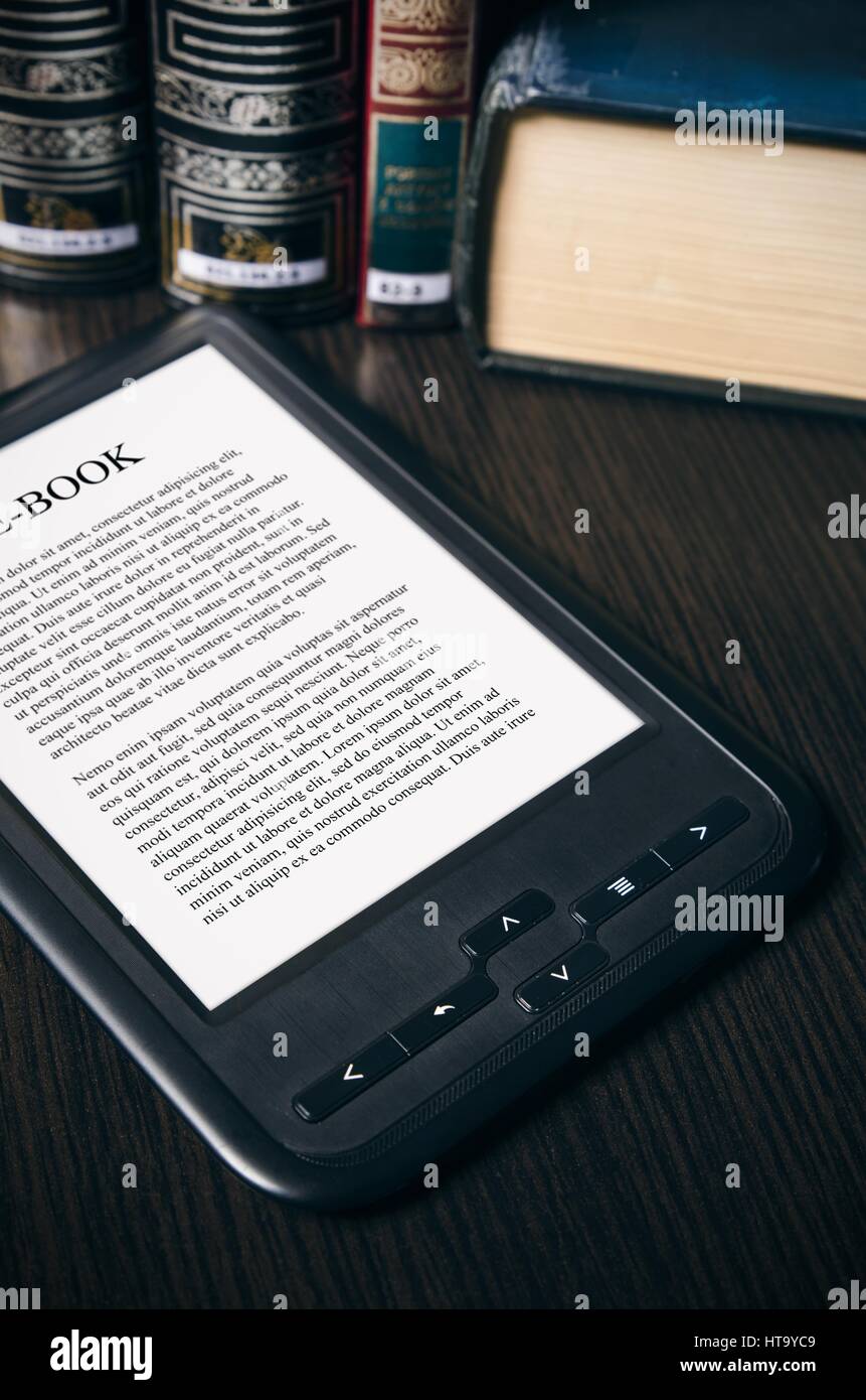 E-book reader device on desk in library. Alternative for traditional ...